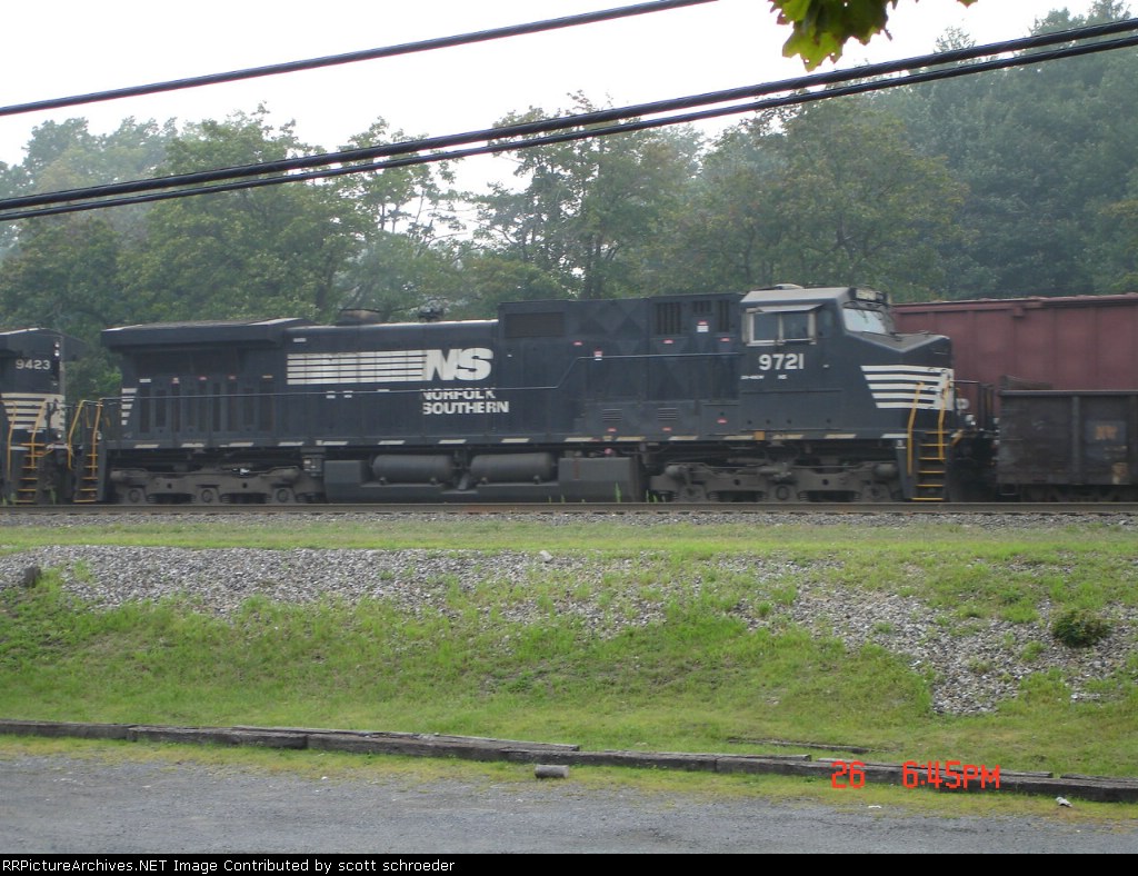 NS 9721 trails long hood forward WB past The Station Inn